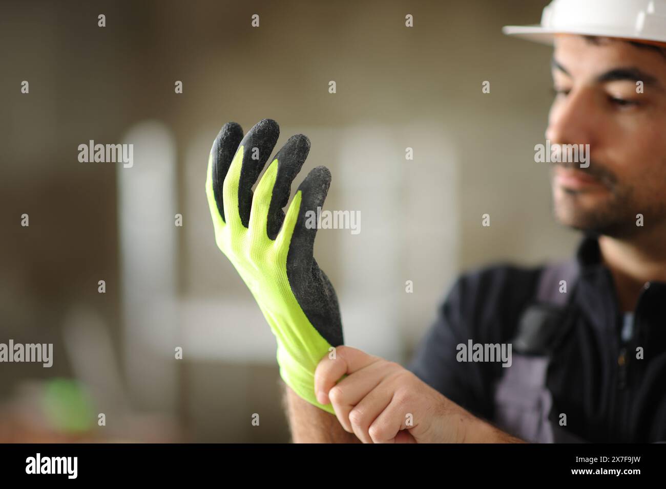 Construction worker putting a yellow protection glove in a house under ...