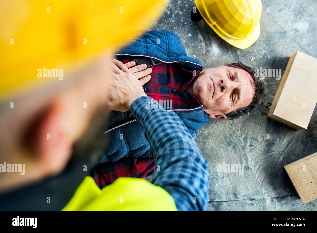 Colleague performing CPR on an injured worker lying on the ground after ...
