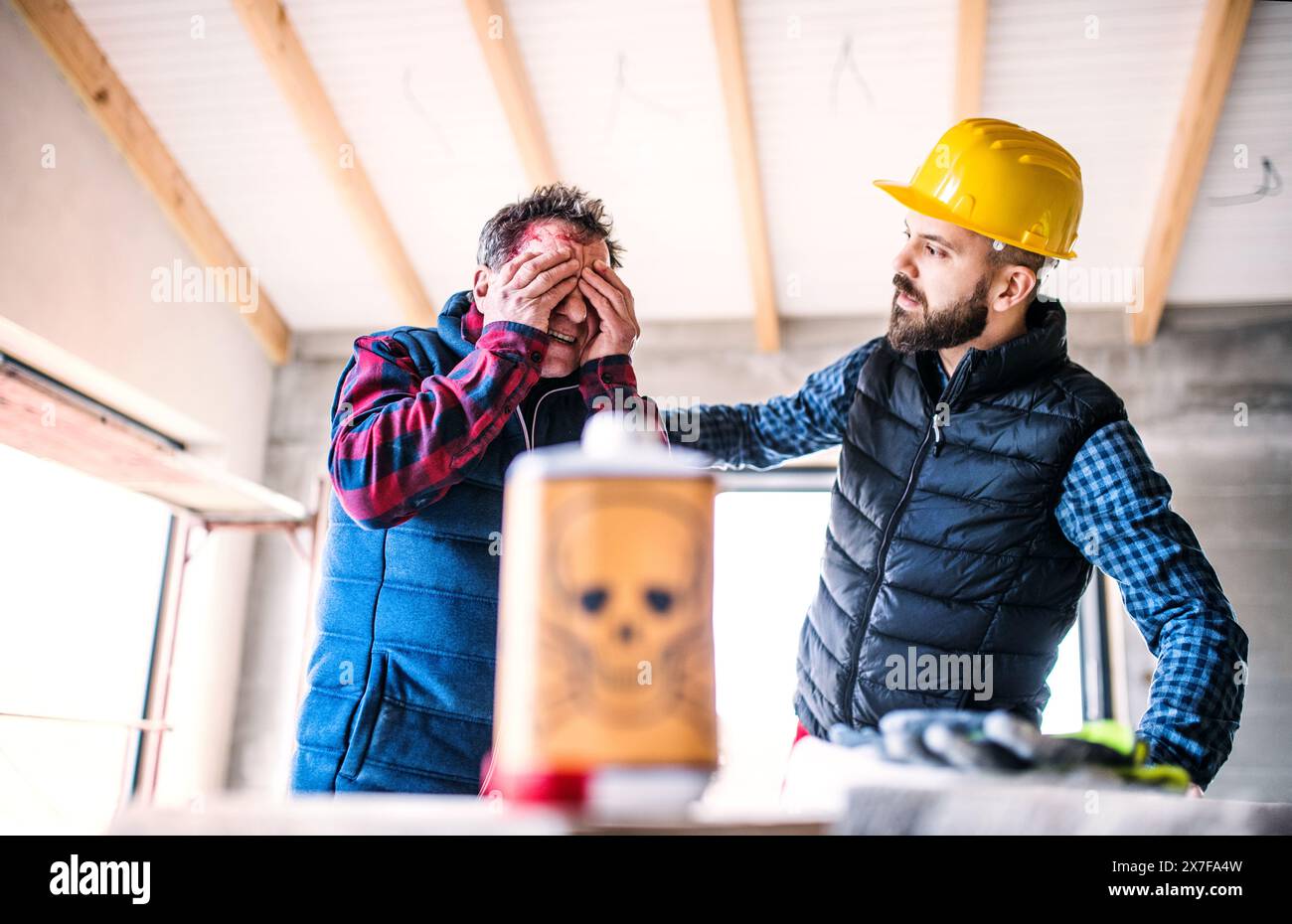 Colleague giving first aid to worker with chemical splashed on his skin ...