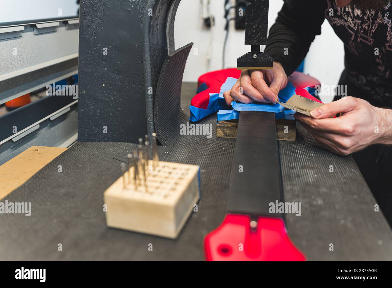 worker adding thread and frets on a guitar at the workshop, guitar ...