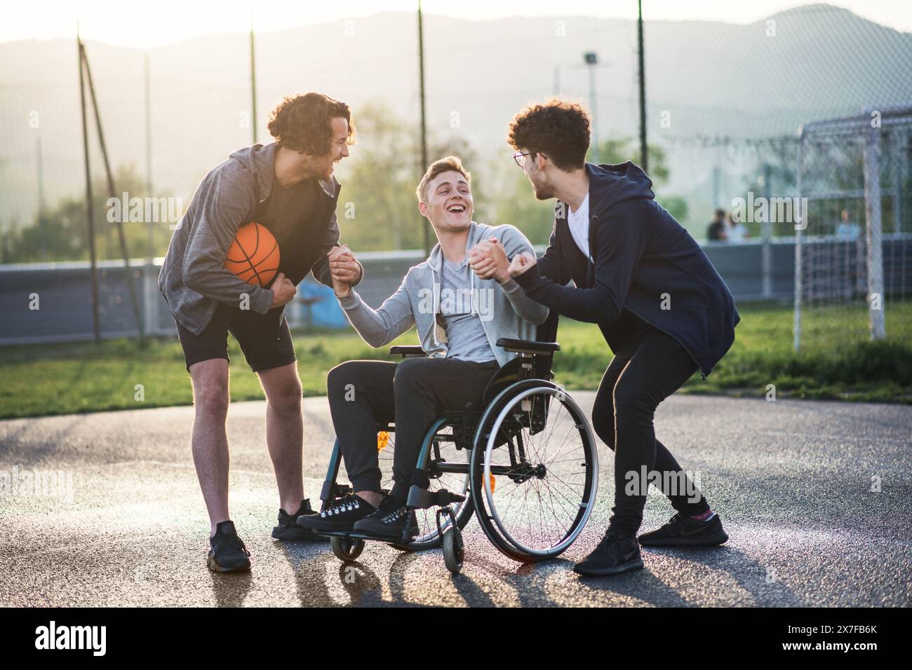 Disabled young man in a wheelchair playing basketball with his friends ...