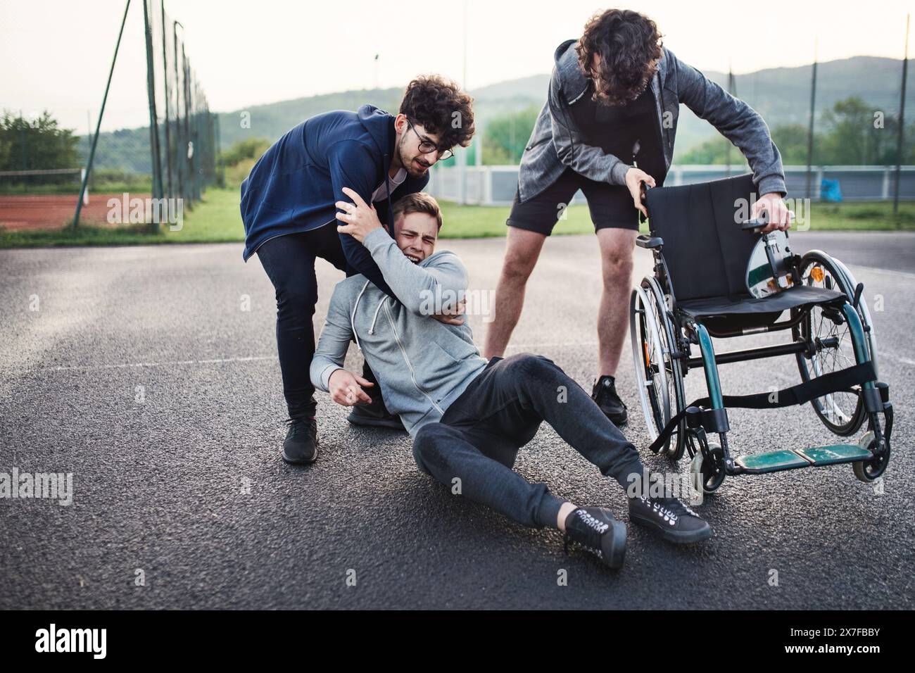 Young disabled man fall off wheelchair, fiends helping to sit back ...