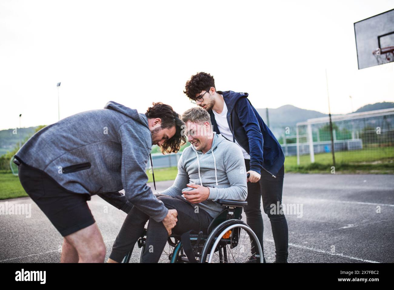 Young man in wheelchair spending free time outdoor with friends ...