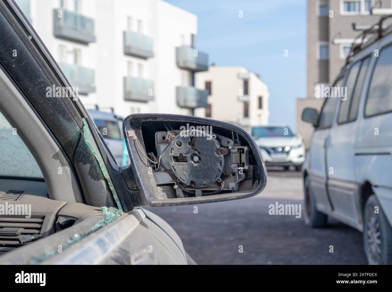 A broken mirror on an abandoned car reflects the damage and neglect it ...