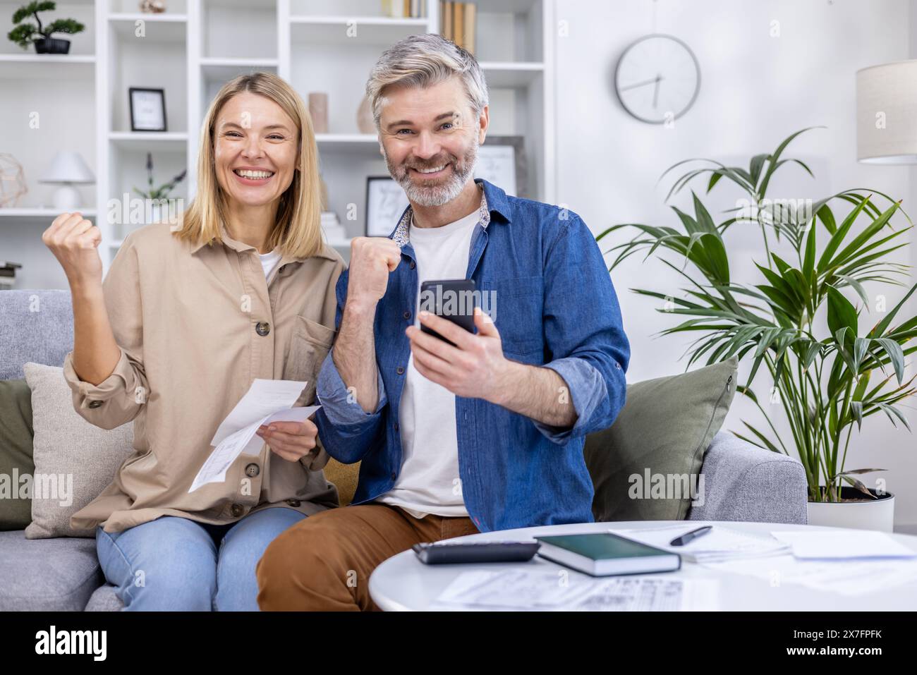 Happy couple celebrating their success with documents and smartphone in ...