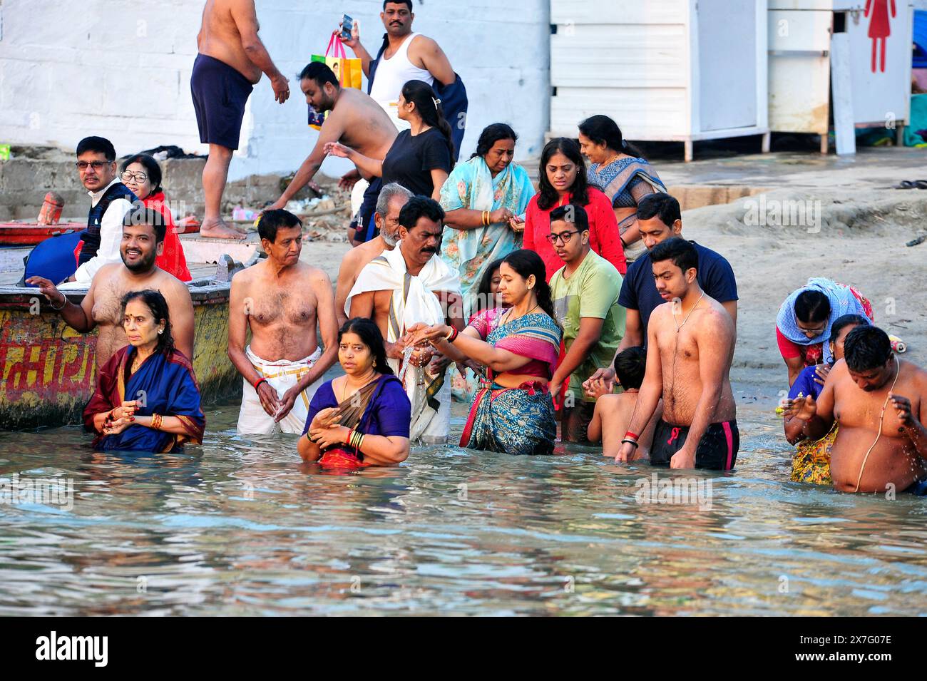 Hindu pilgrims bathing in the sacred river Ganges and pray, Varanasi ...