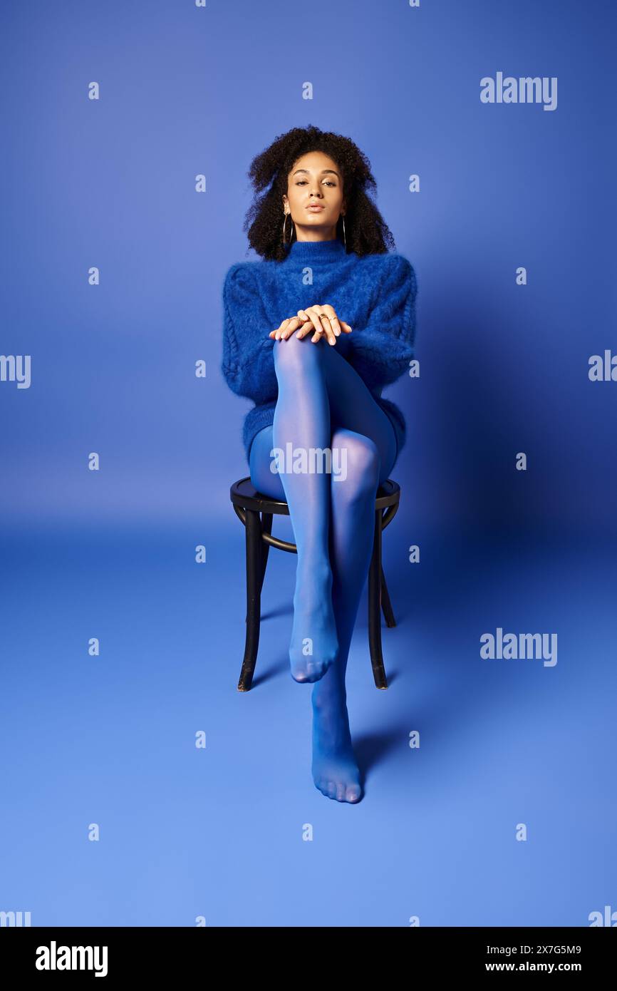 A young woman sits gracefully in a chair with her legs crossed, wearing ...