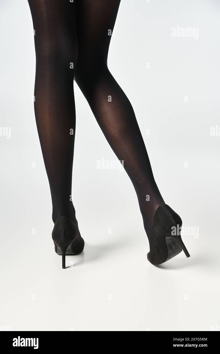 A young woman showcases her legs adorned in black stockings and high ...