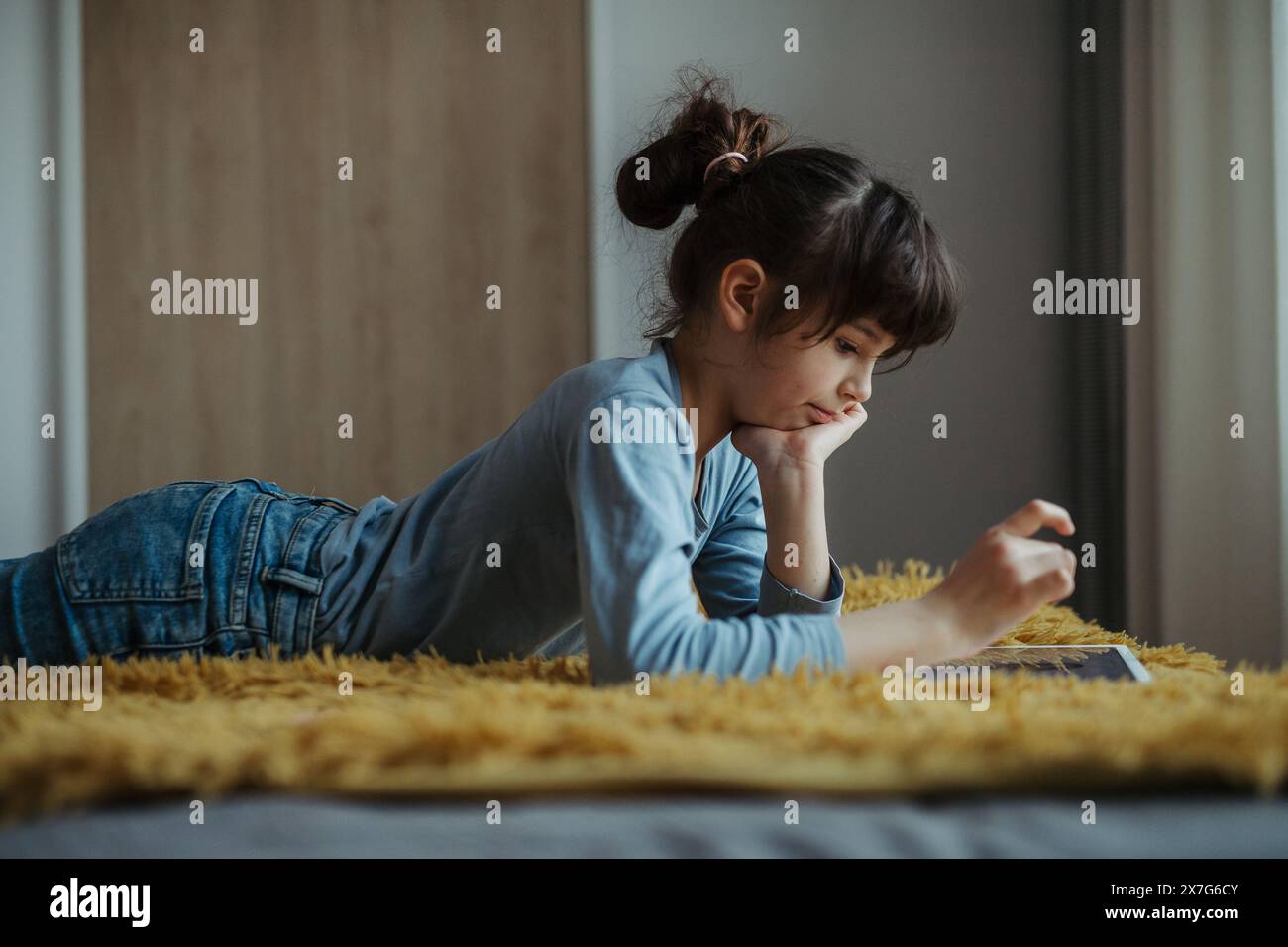 Cute girl lying on belly, scrolling on smartphone. Using social media ...