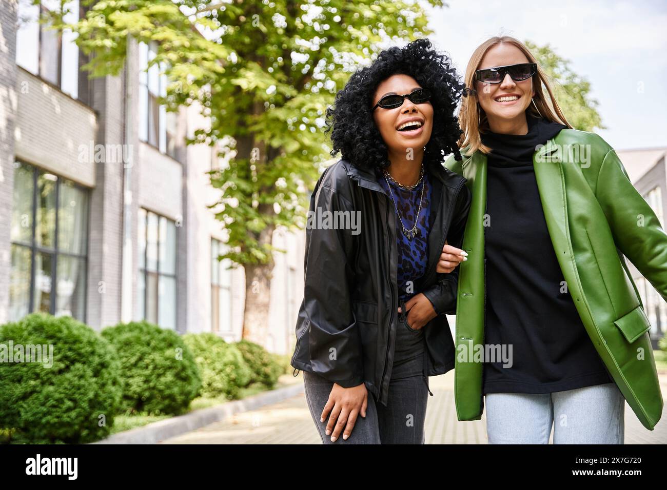 Two attractive diverse women walk together down a city street in cozy ...