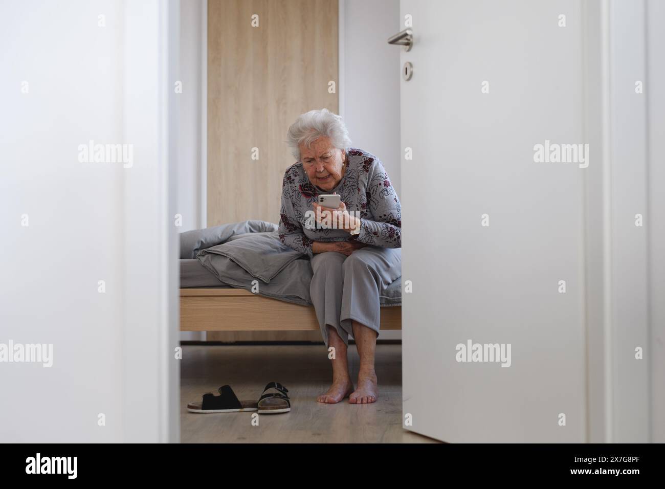 Senior woman trying to stand up from bed, feeling pain Stock Photo - Alamy
