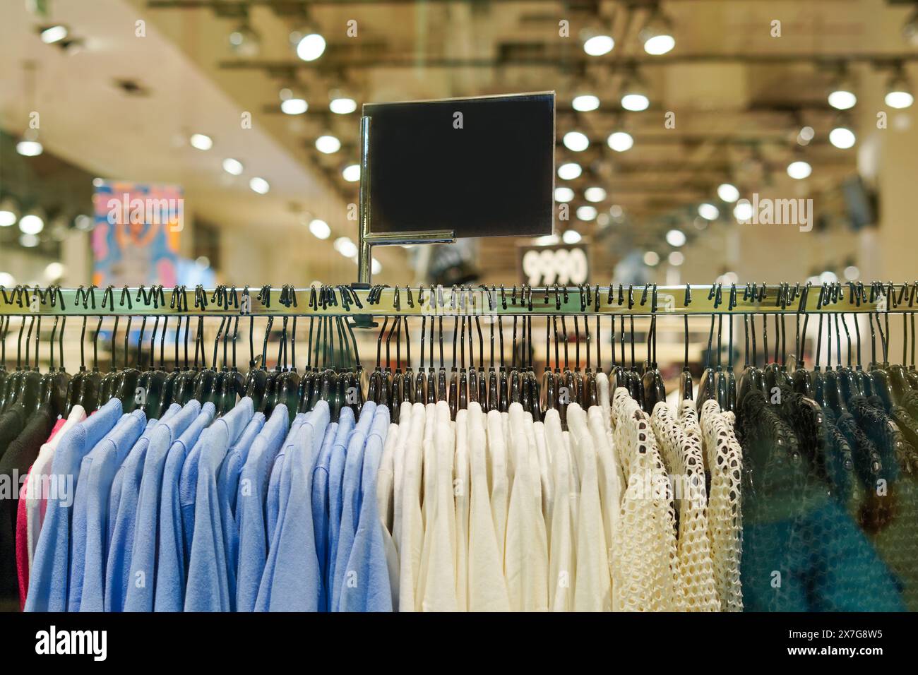 Clothes on hangers with black sign for text in a retail shop . Fashion ...