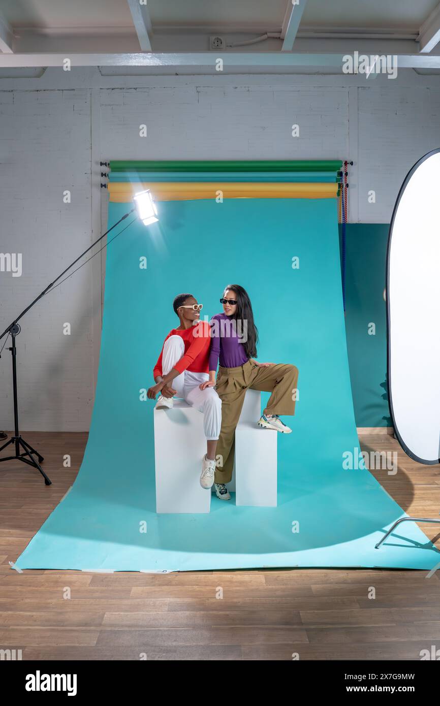 Two women pose on a color background cyclorama in a studio photo shoot ...