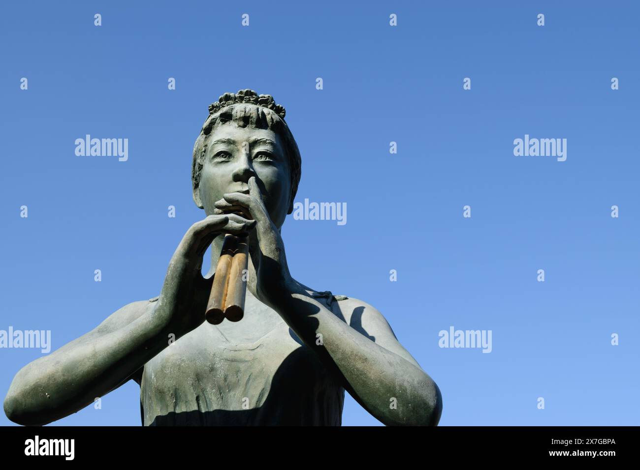 Statue of a woman playing a flute against a clear blue sky Stock Photo ...