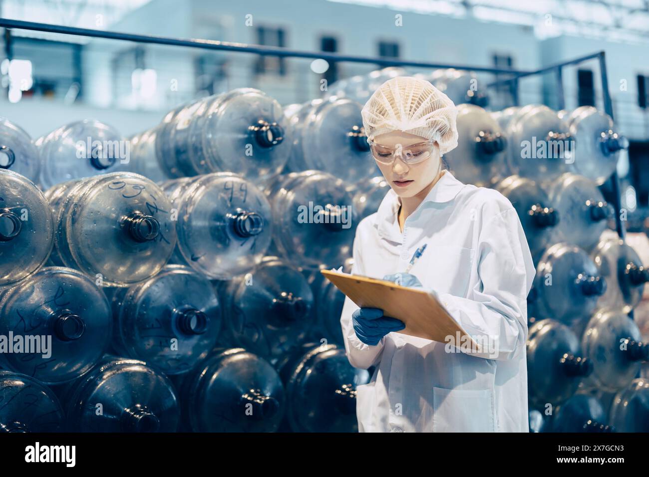 Young Caucasian women worker work in drink water factory counting check ...