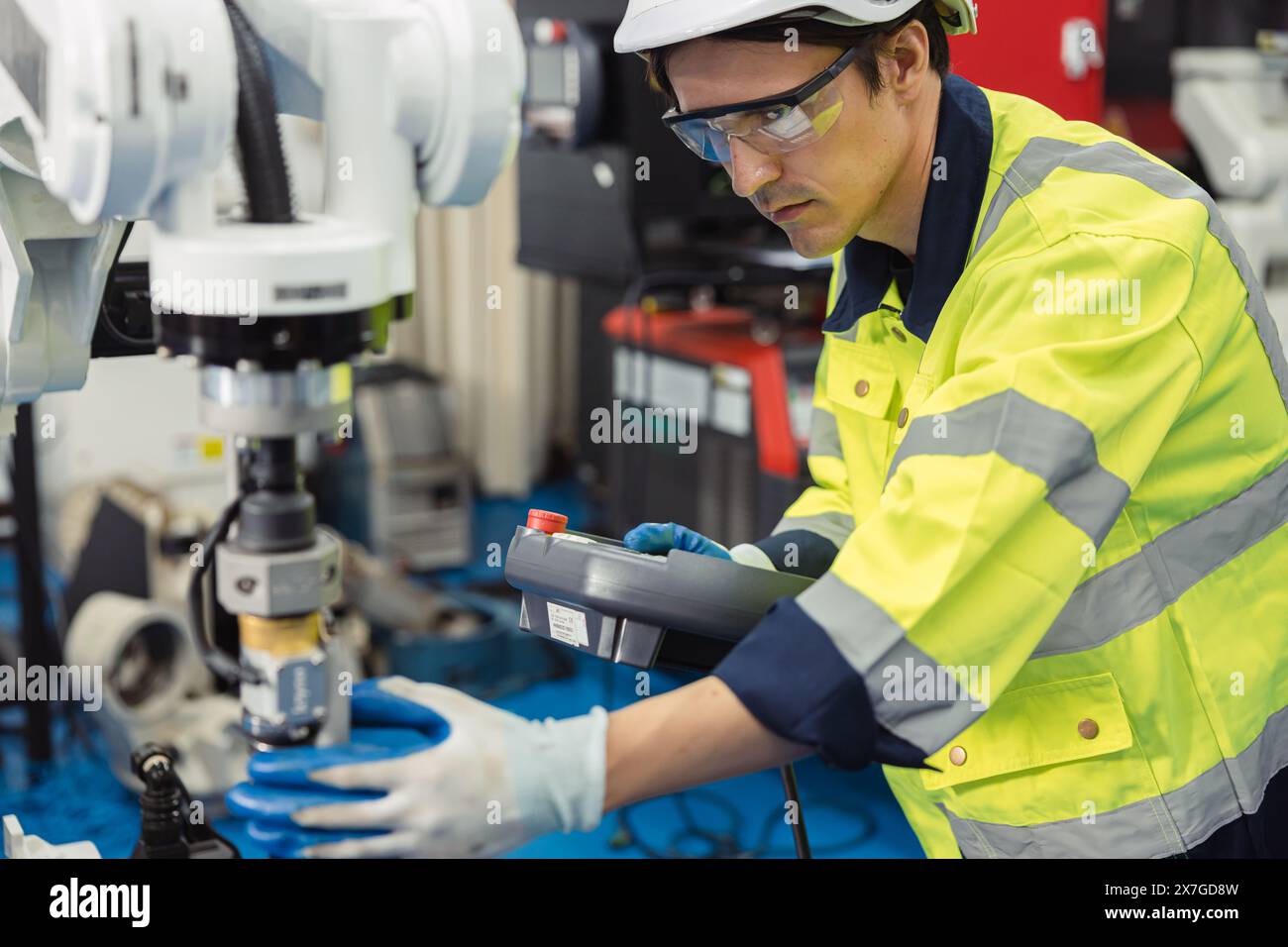 Engineer young man university student learn to control operate industry robot welding arm in ...