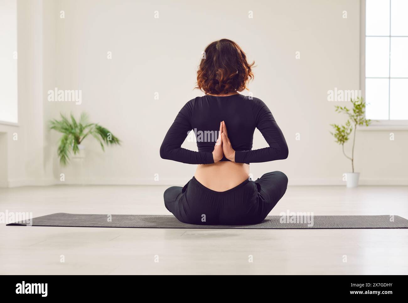 Yogi woman rear view practicing yoga, sitting in Ardha Padmasana ...