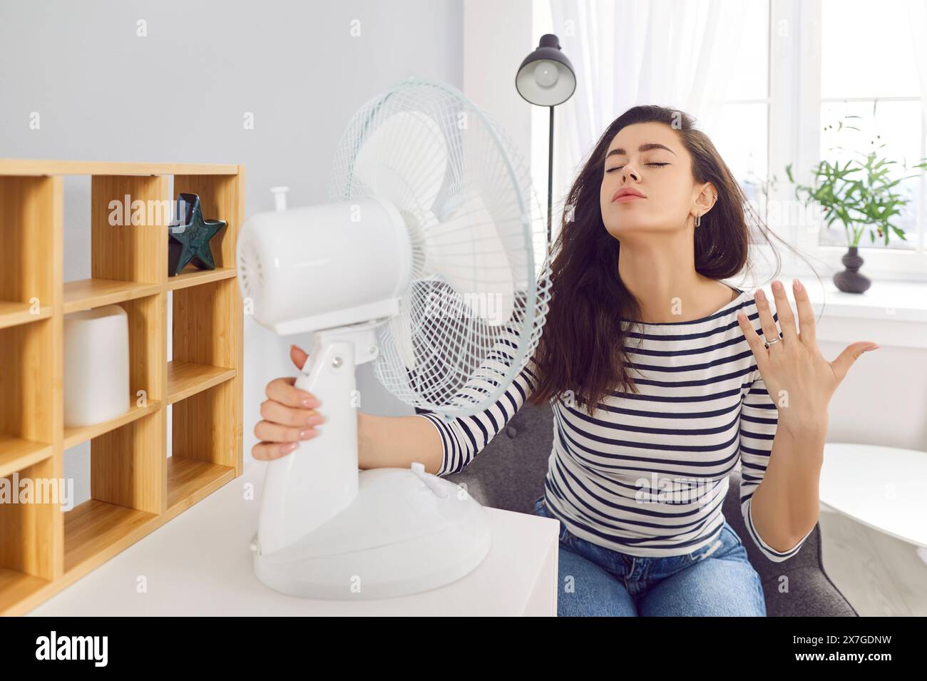 Woman feels unwell due to summer heat and cools down at home in front ...