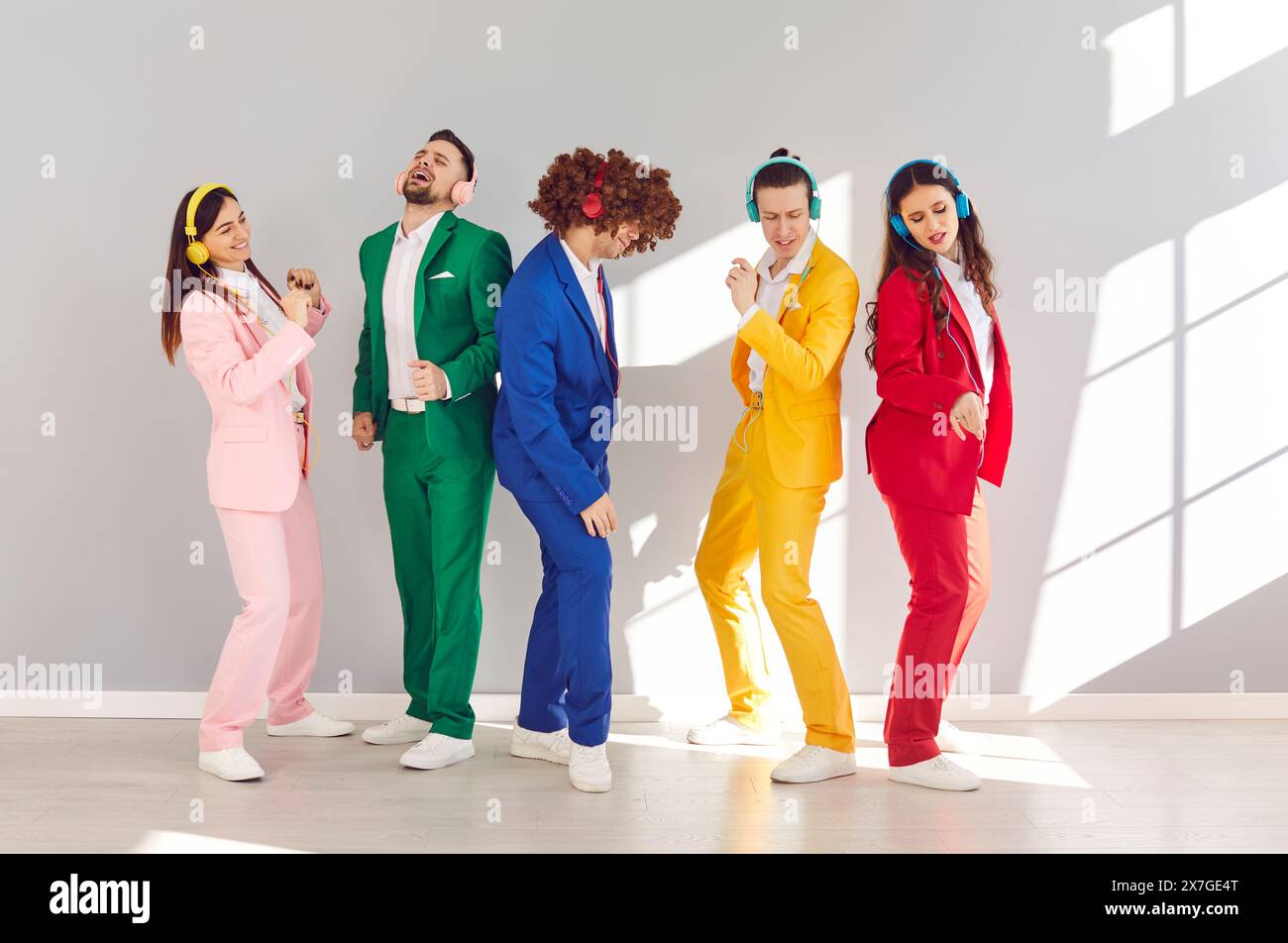 Group Of Young People In Colorful Suits Listening To Music And Dancing ...