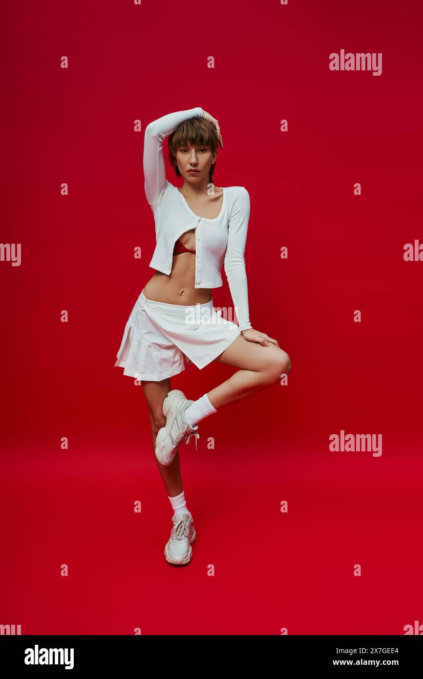 A stylish young woman in a short skirt and crop top energetically ...