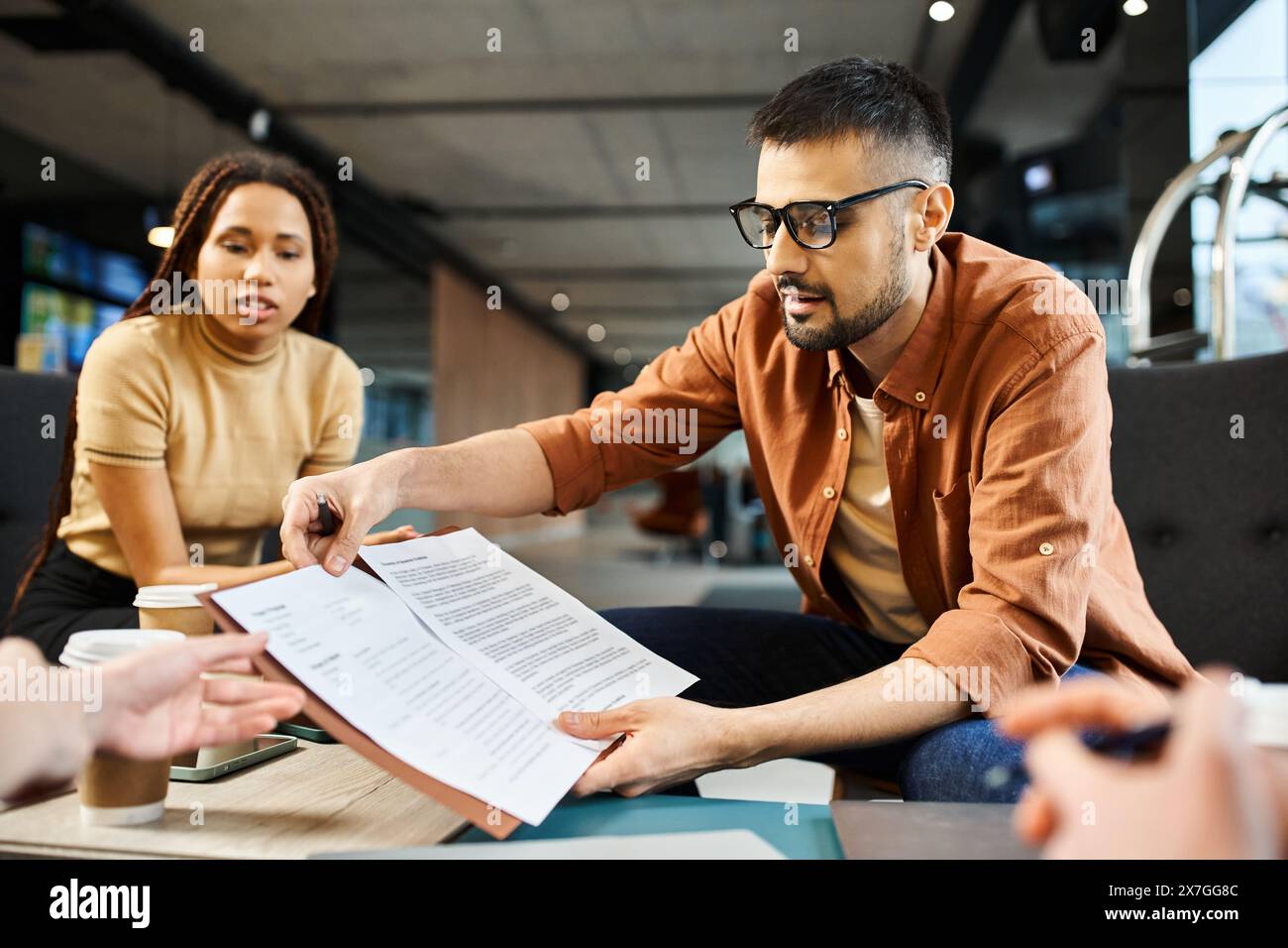 A diverse group of colleagues gather around a table, discussing papers ...