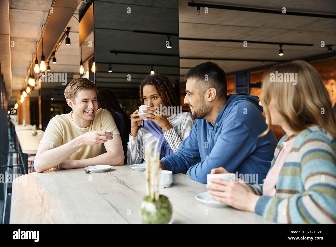Diverse colleagues from a modern startup team gather around a table ...