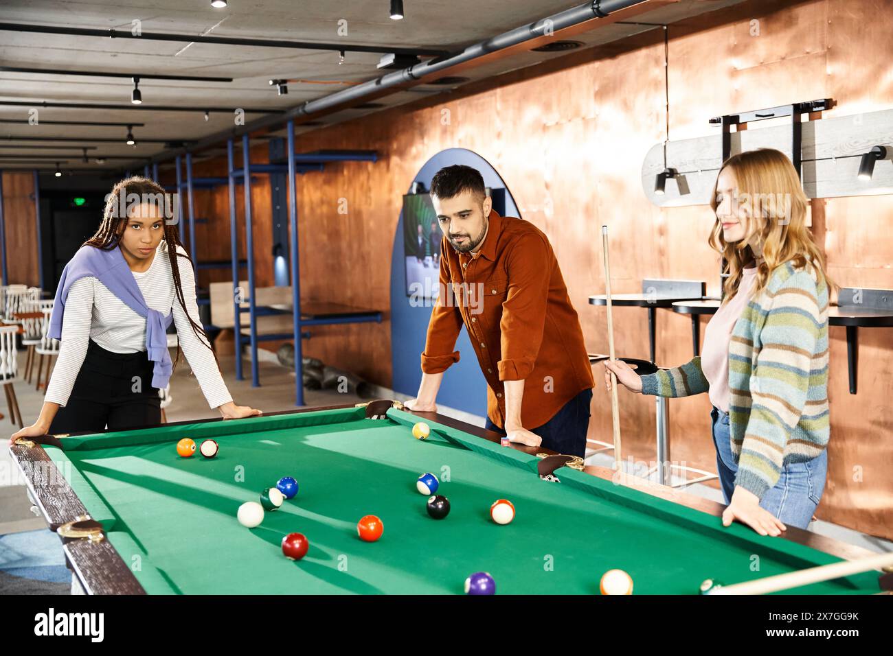 A group of startup colleagues enjoy a friendly game of pool ...