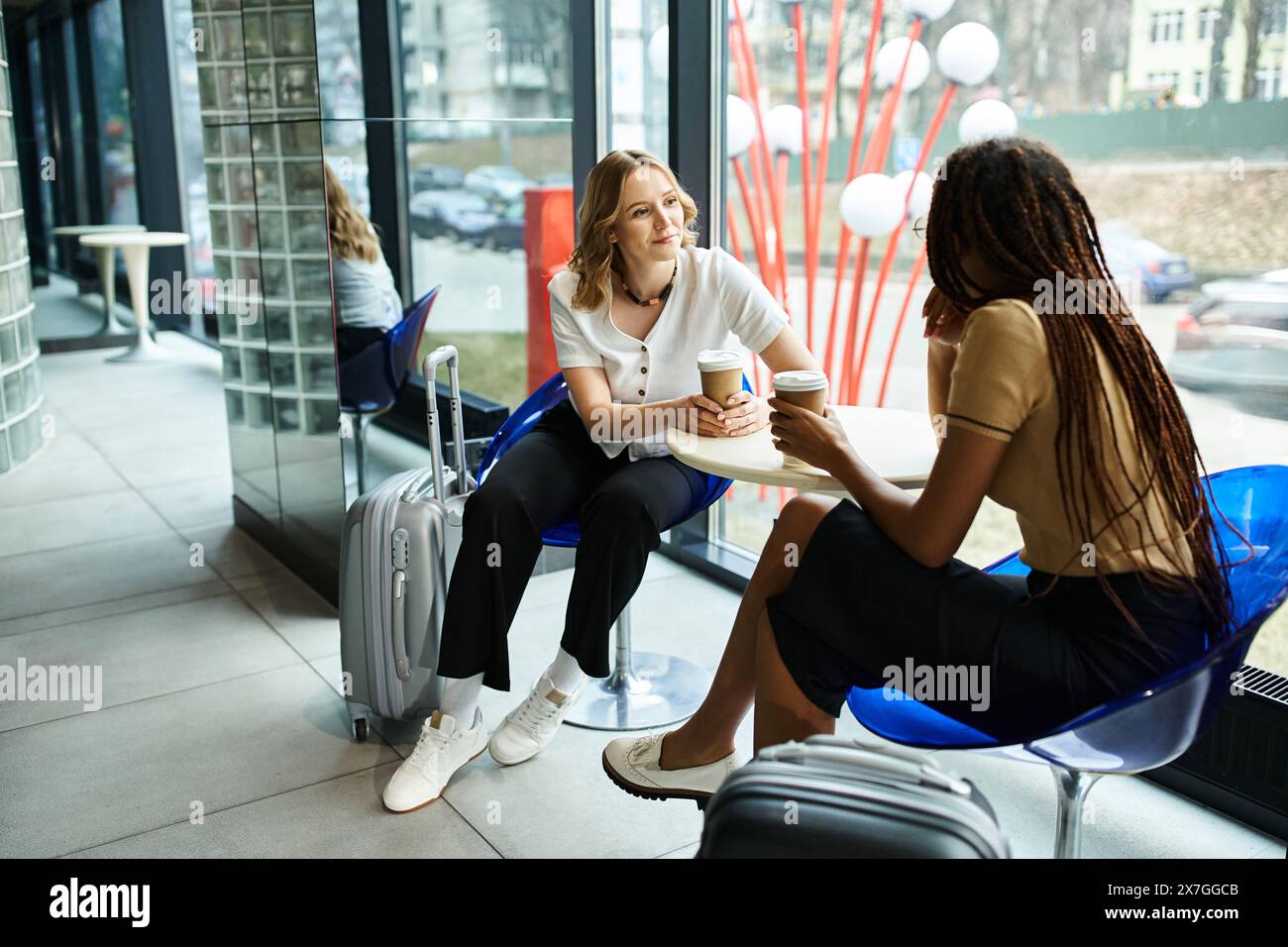 Two diverse businesswomen are seated in chairs, sharing a conversation ...