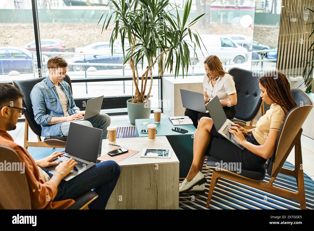 A diverse group of colleagues collaborating on laptops in a vibrant ...