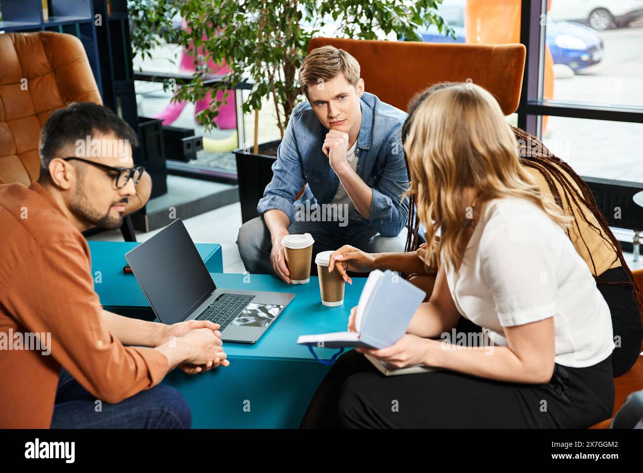 Multicultural colleagues working together around table with laptop in ...