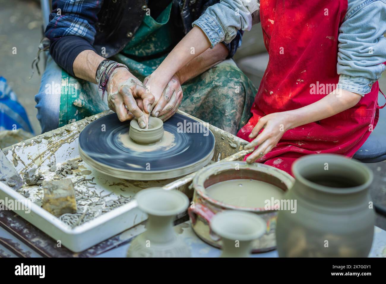 Man and a child are making pottery. The man is teaching the child how ...