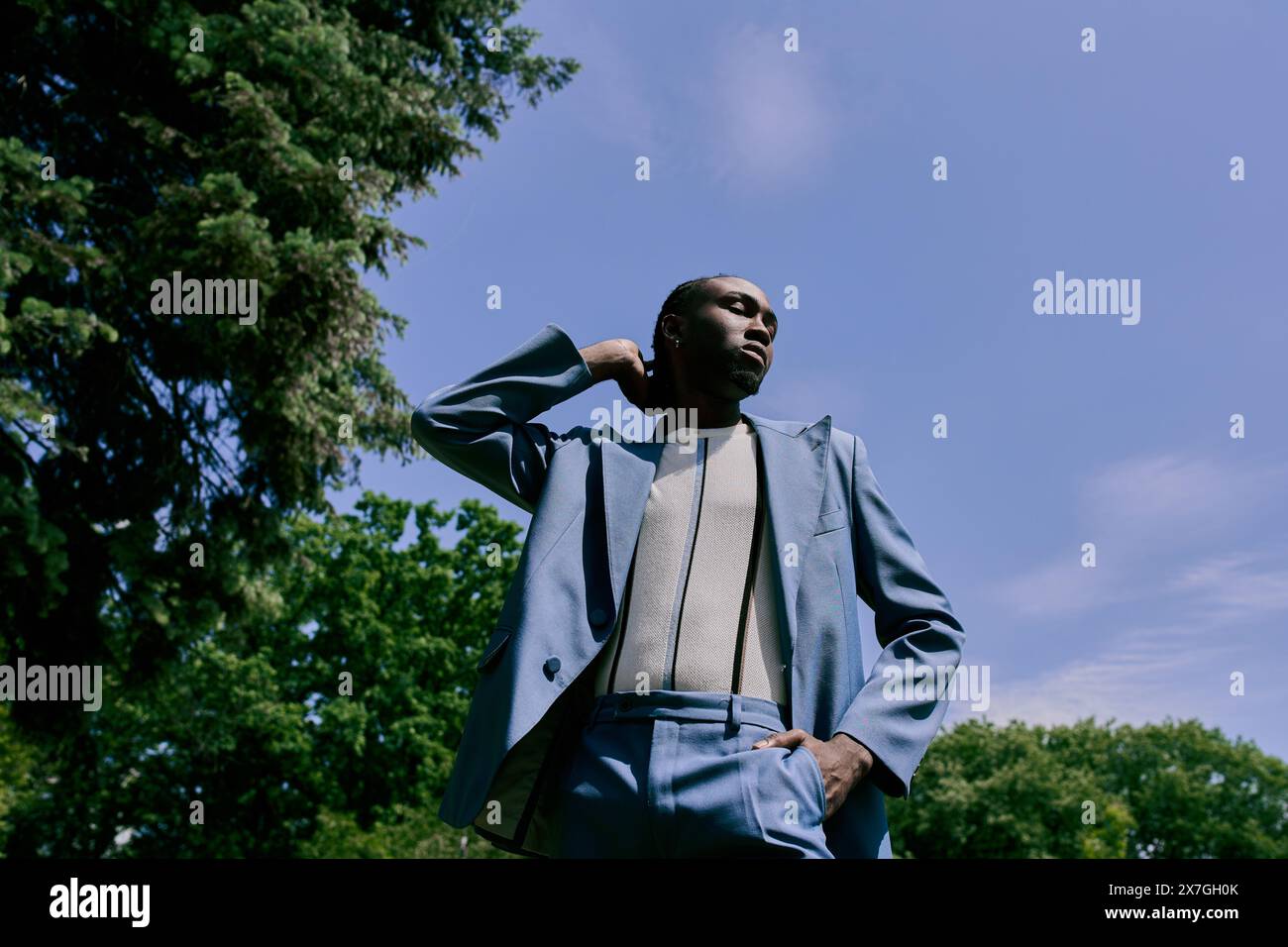 A sophisticated African American man in a suit and tie stands elegantly ...