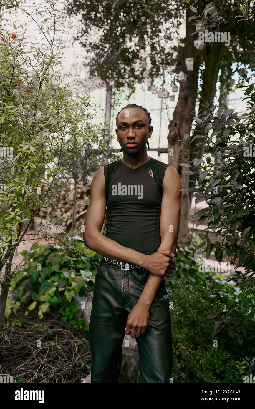 A dapper African American man stands elegantly next to a towering tree ...