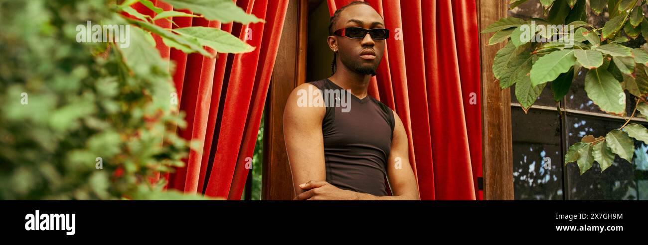 A sophisticated man strikes a pose in front of a vibrant red curtain ...