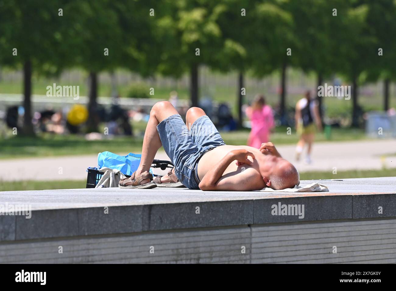Aelterer Mann sonnt sich im Riemer Park in Muenchen. Er liegt auf einer ...
