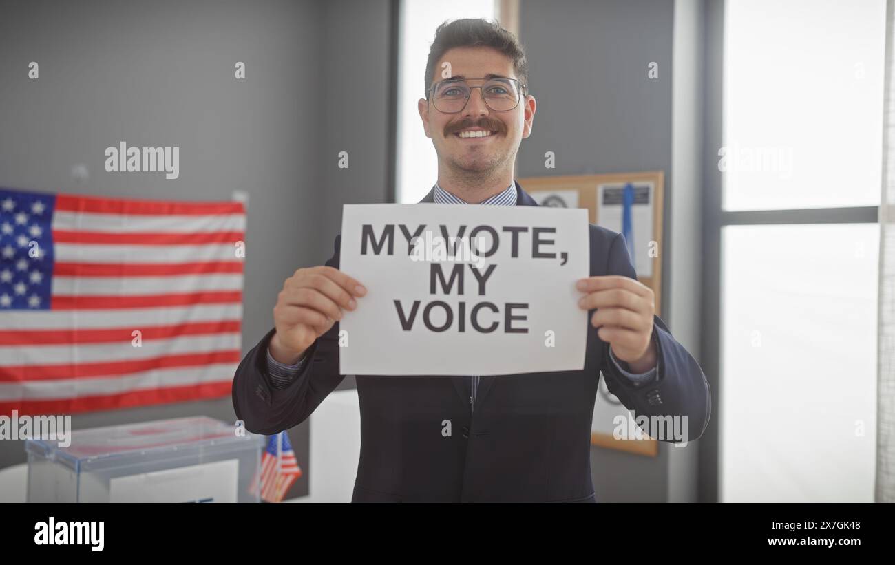 Smiling young hispanic man holding 'my vote, my voice' sign in a voting ...