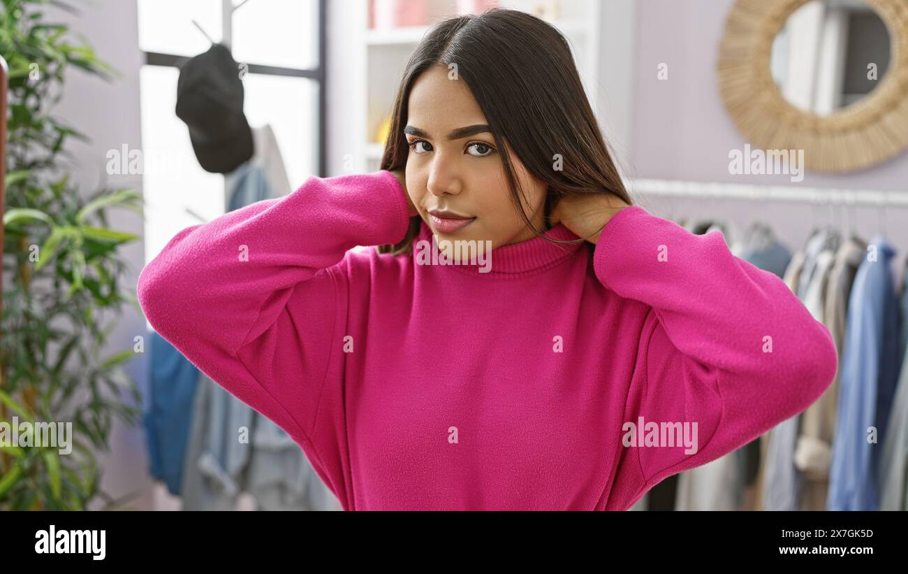 A confident young hispanic woman poses in a pink sweater inside a ...