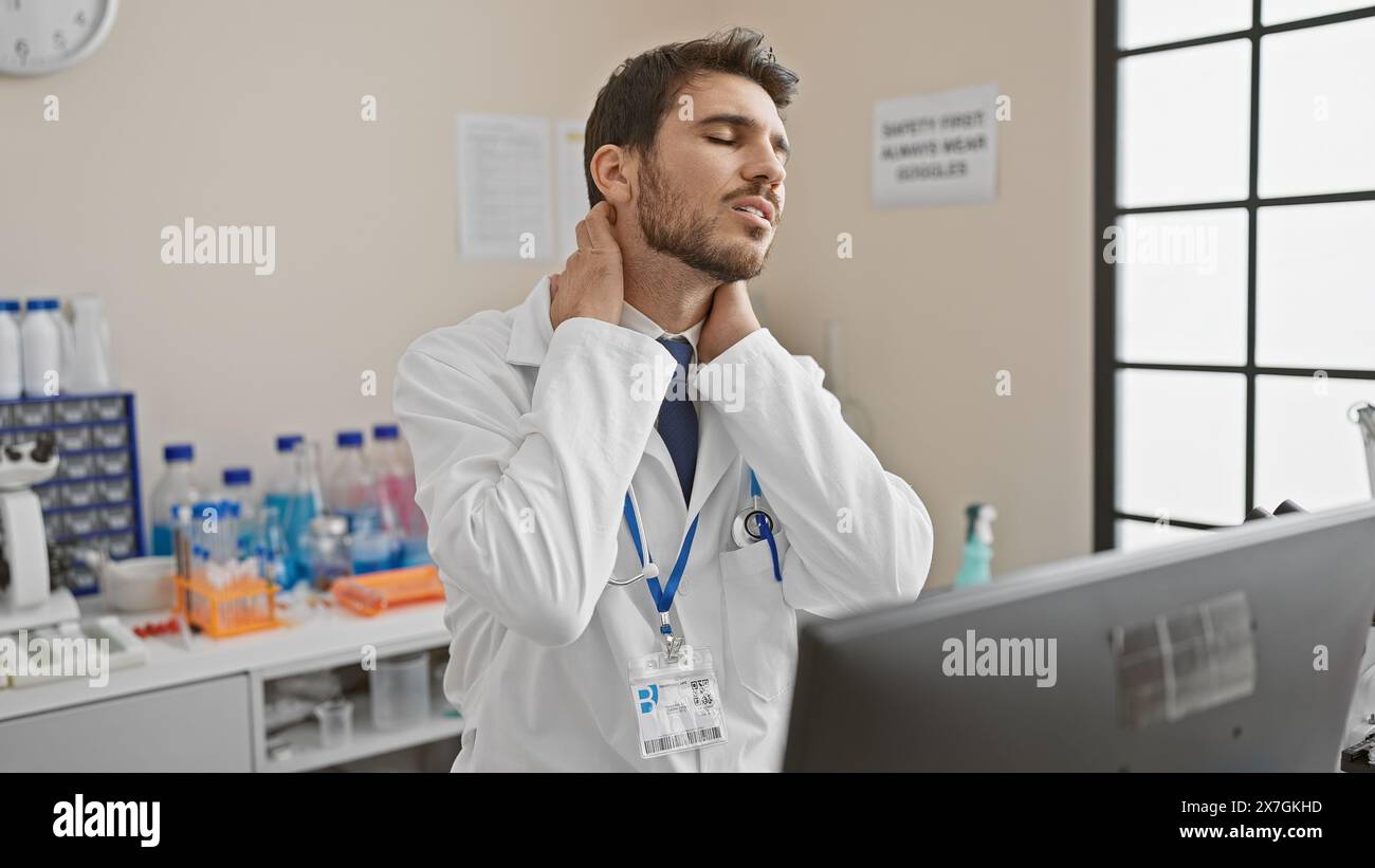 Hispanic man in lab coat feeling neck pain inside hospital laboratory ...