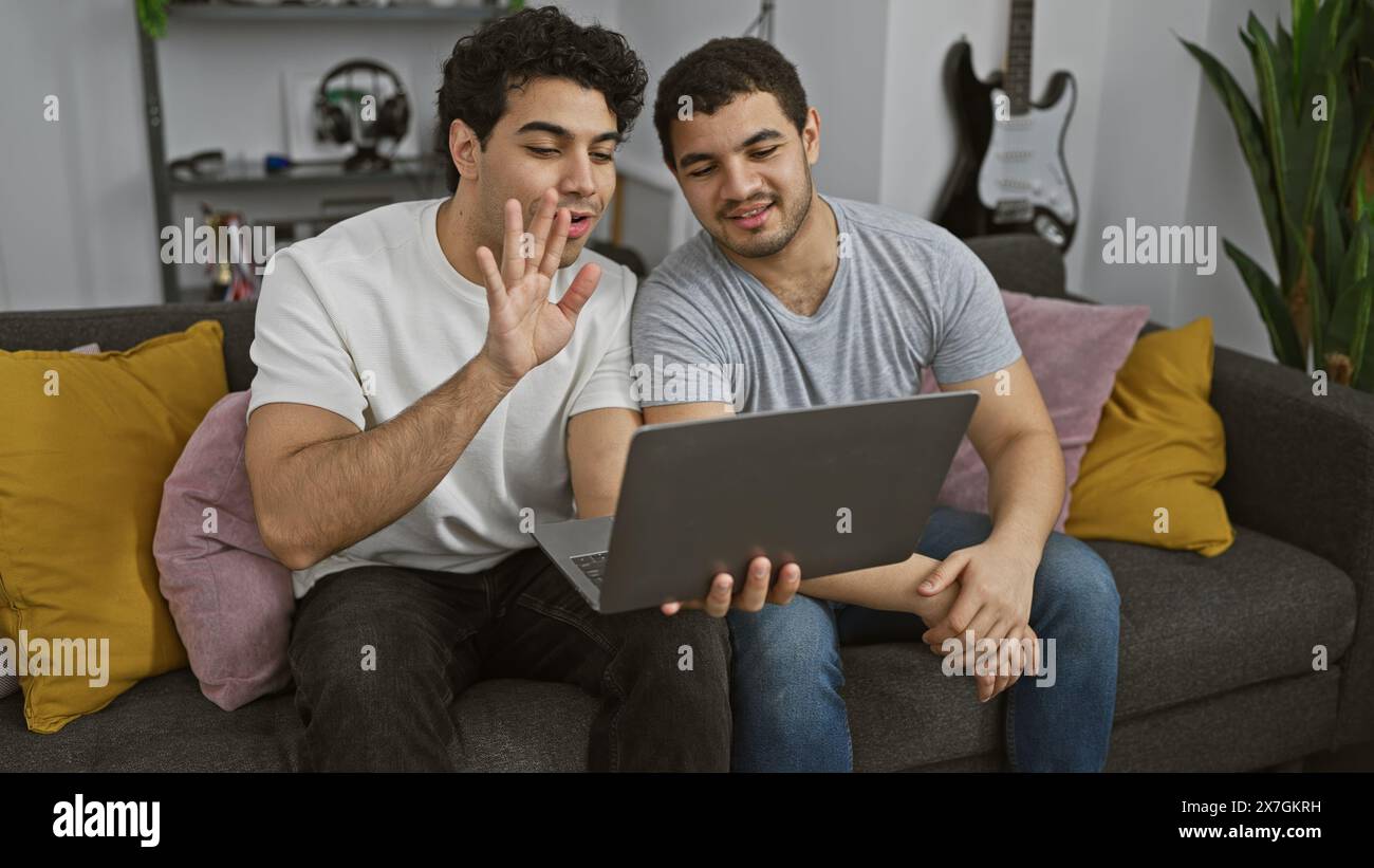 Two men interacting with a laptop on a couch in a home environment ...