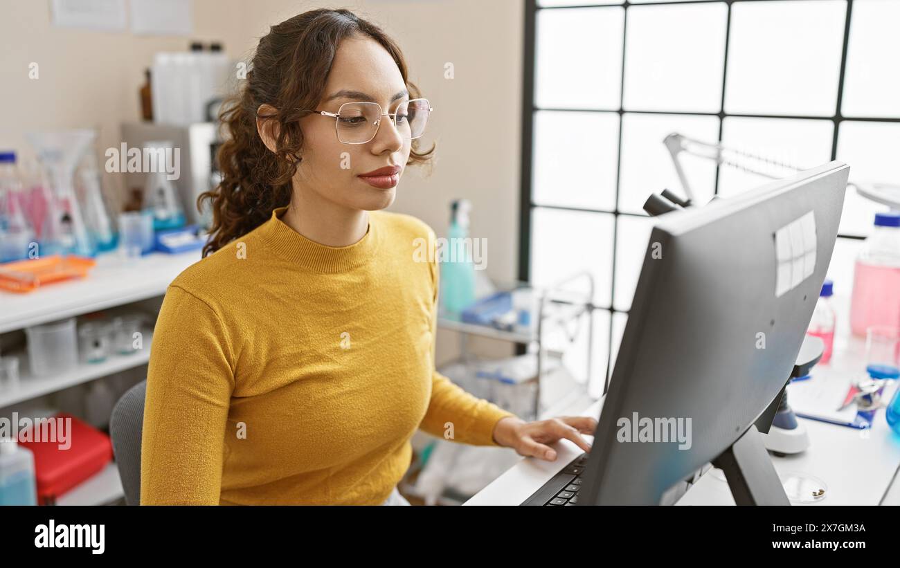 A focused woman works on a computer in a modern lab, portraying ...