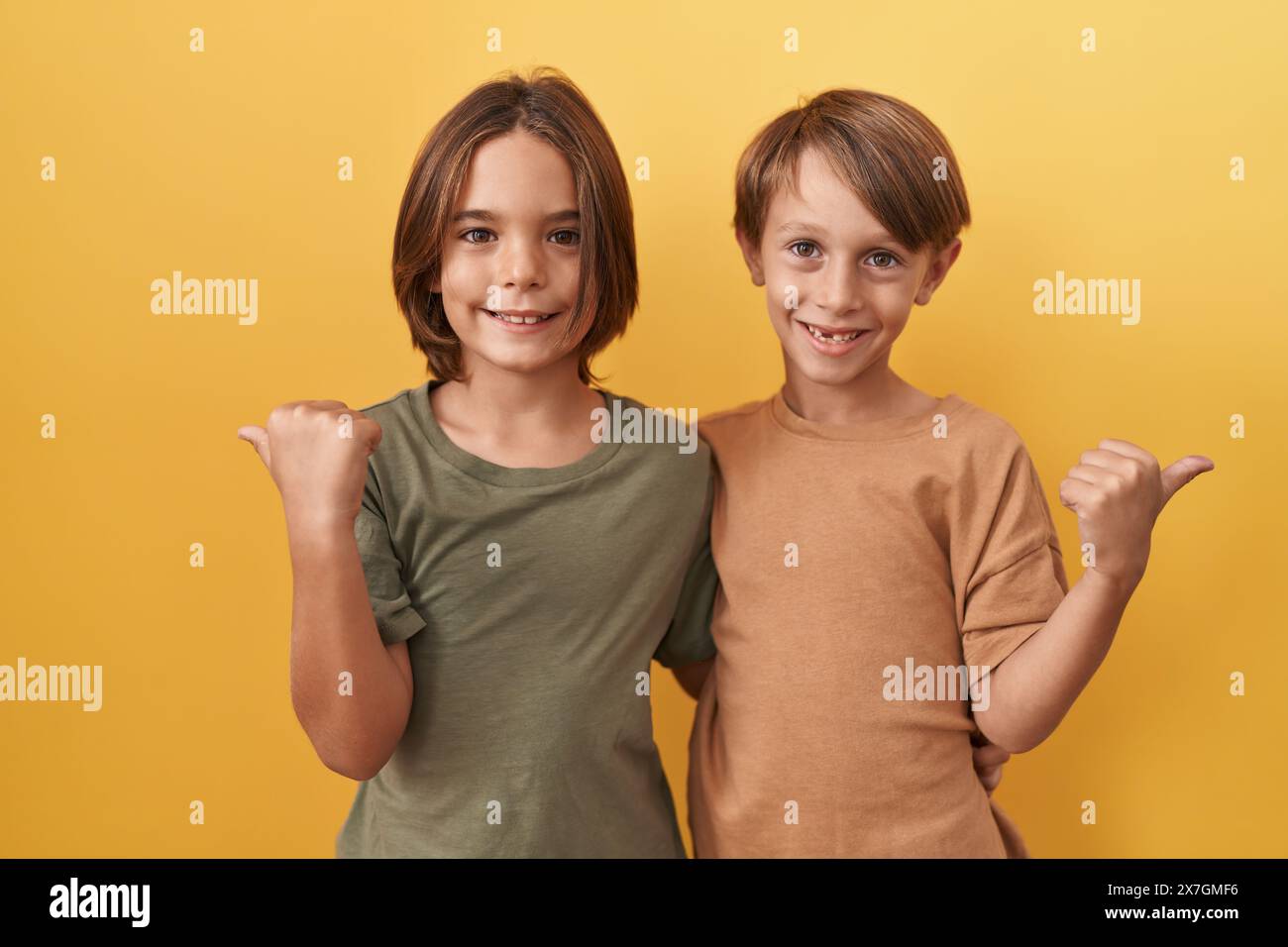Two adorable boys, together, standing and hugging cheerfully; happily ...