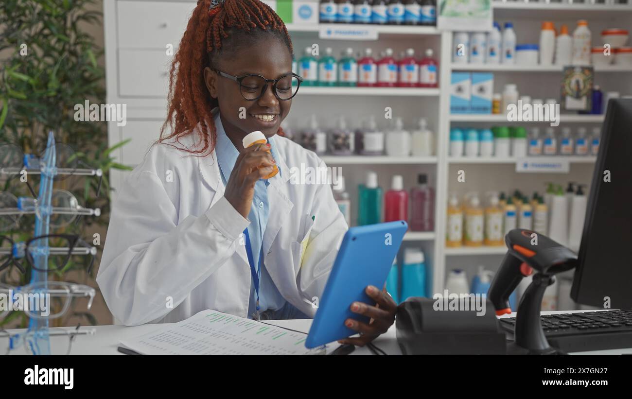 African female pharmacist using a tablet inside a well-stocked pharmacy ...