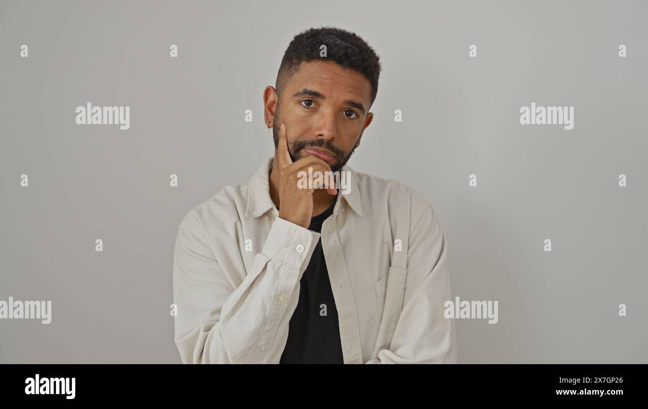 A thoughtful young man with a beard poses against a white background ...
