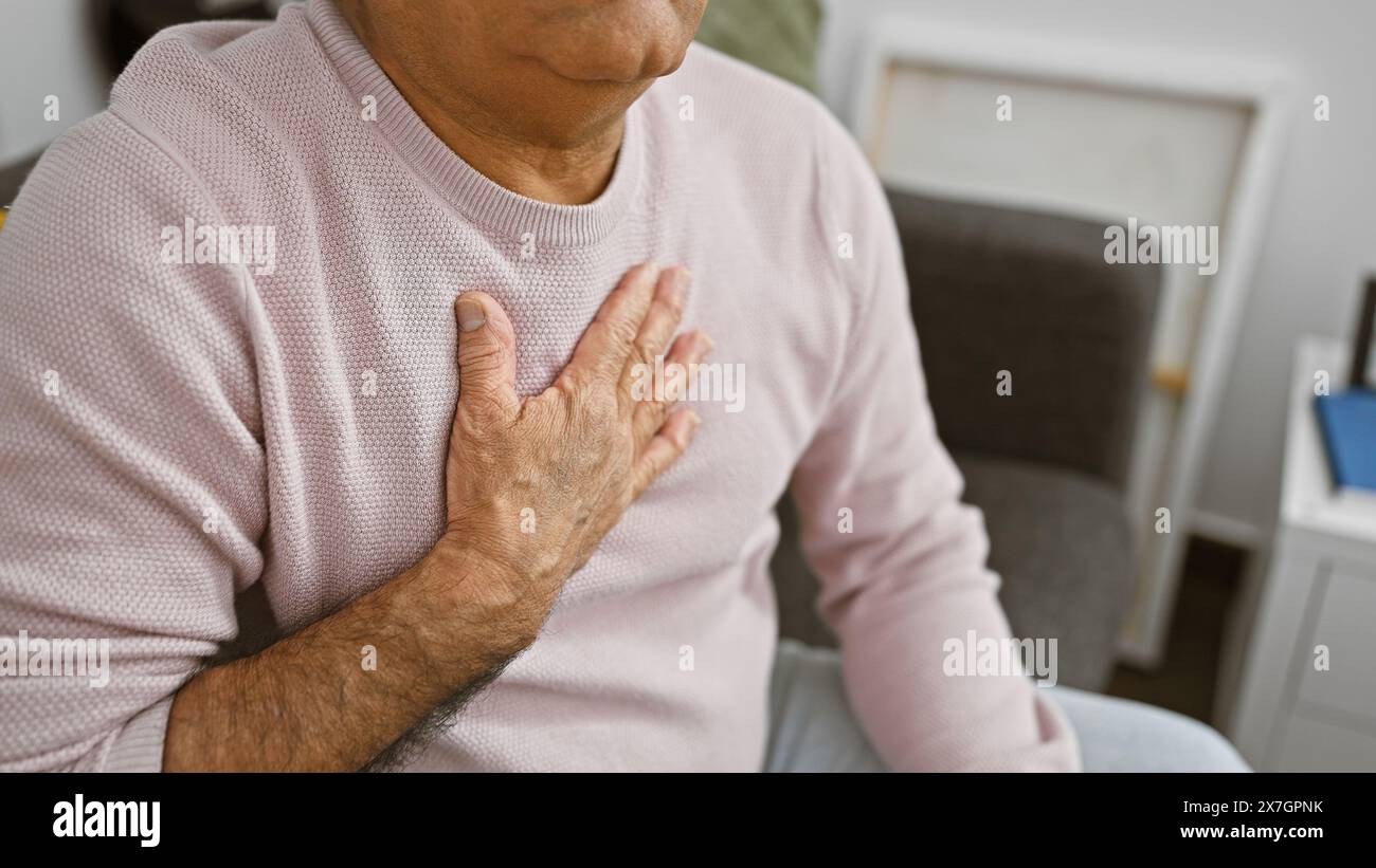 A senior man clutching his chest in a living room, portraying potential ...