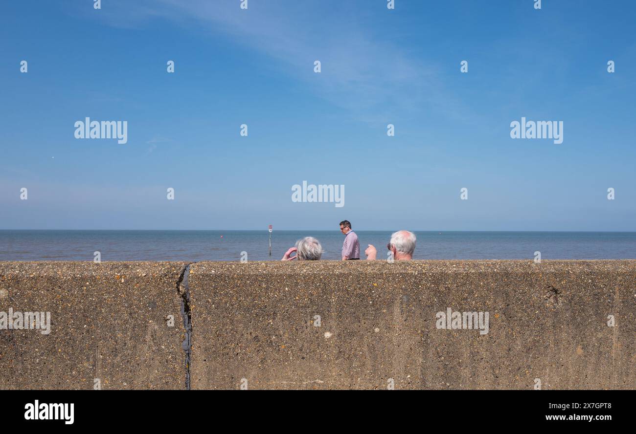 Two elderly couple pointing and looking out to sea and sitting in front ...