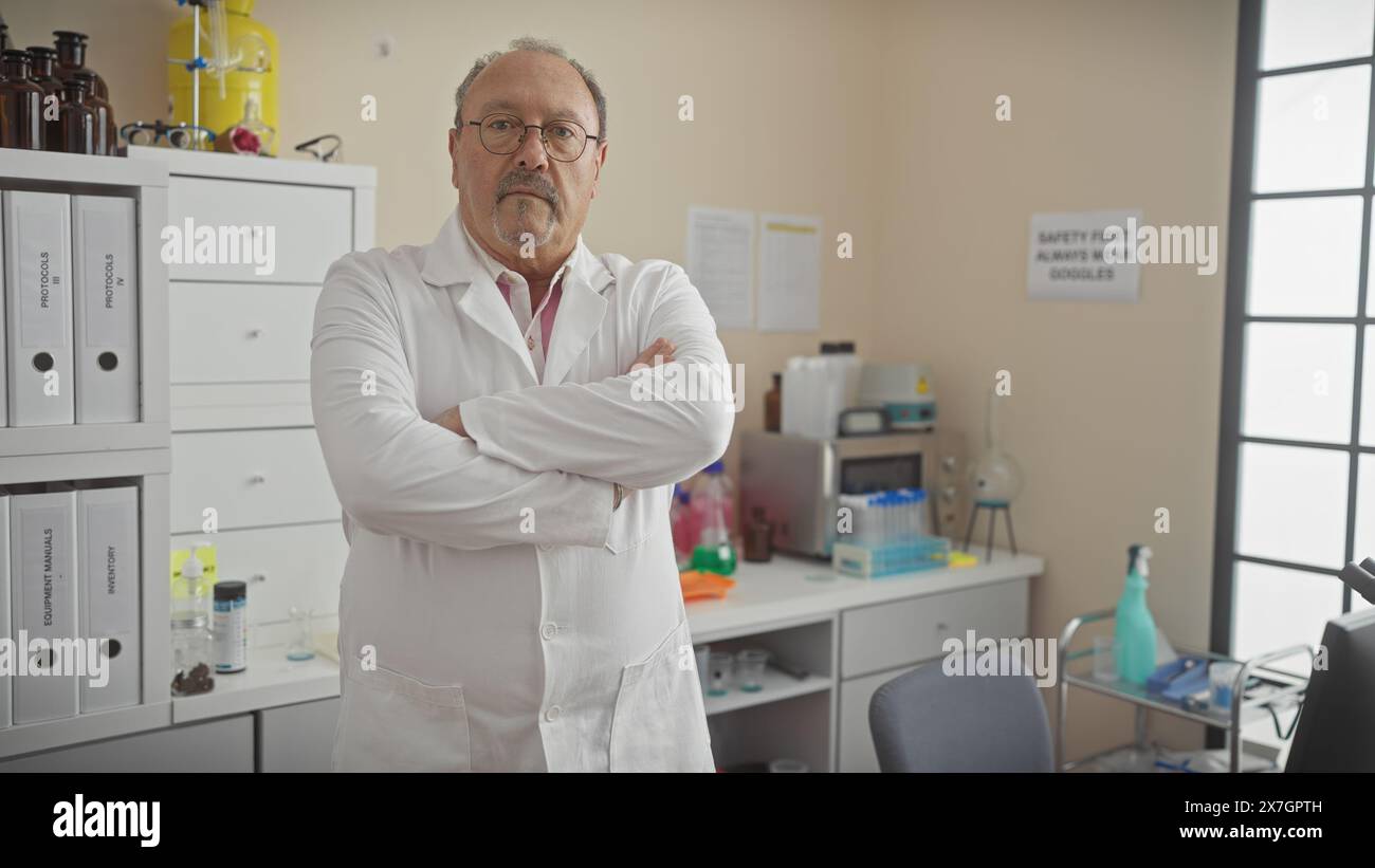 Confident mature man in lab coat standing with arms crossed in a well ...