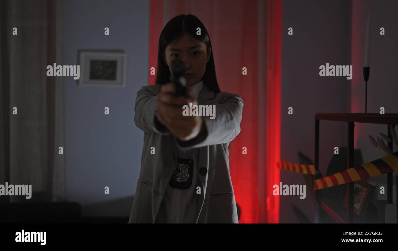 A young asian woman detective with a badge points a gun indoors at a ...