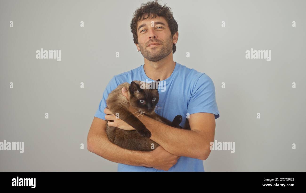 A contented young man embraces a siamese cat, both isolated on a clean ...