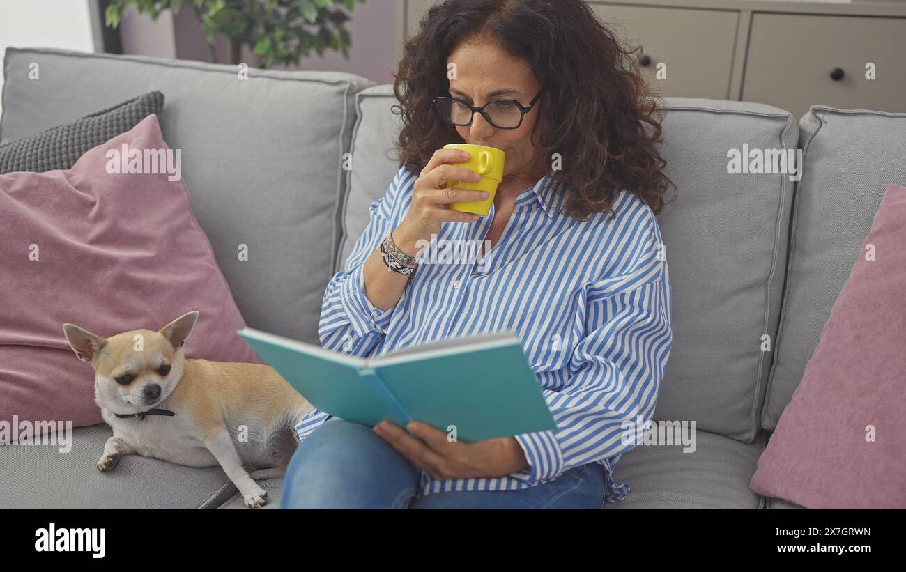 A middle-aged hispanic woman enjoys reading and coffee with her pet chihuahua in a cozy living ...