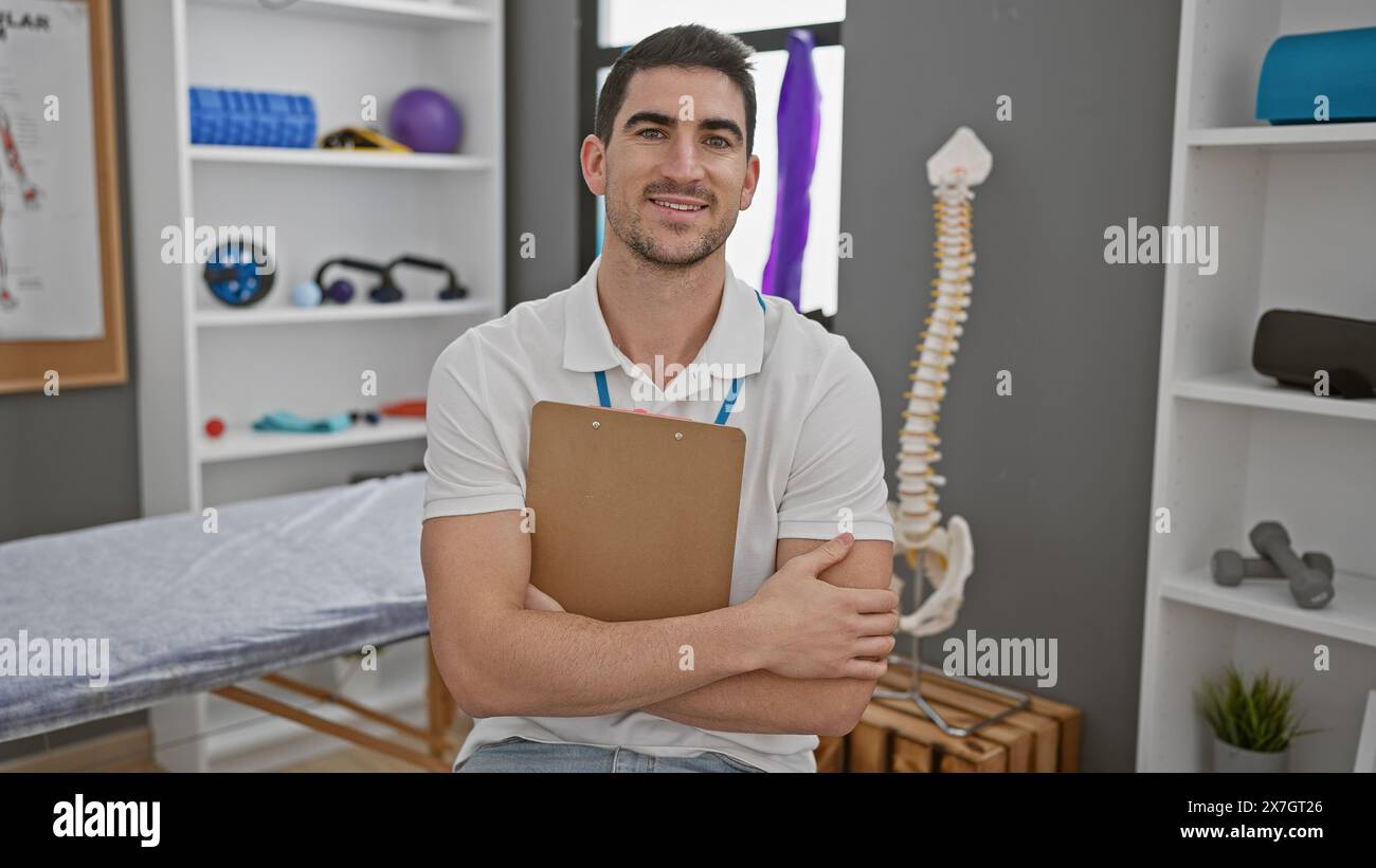 A smiling young man in a white polo shirt holding a clipboard inside a well-equipped ...